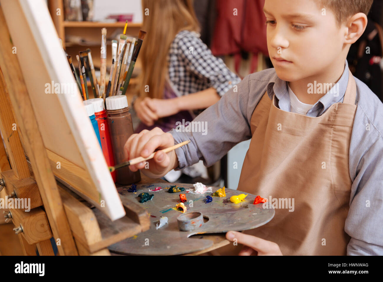 Talented young generation. Cute concentrated capable boy sitting in the ...