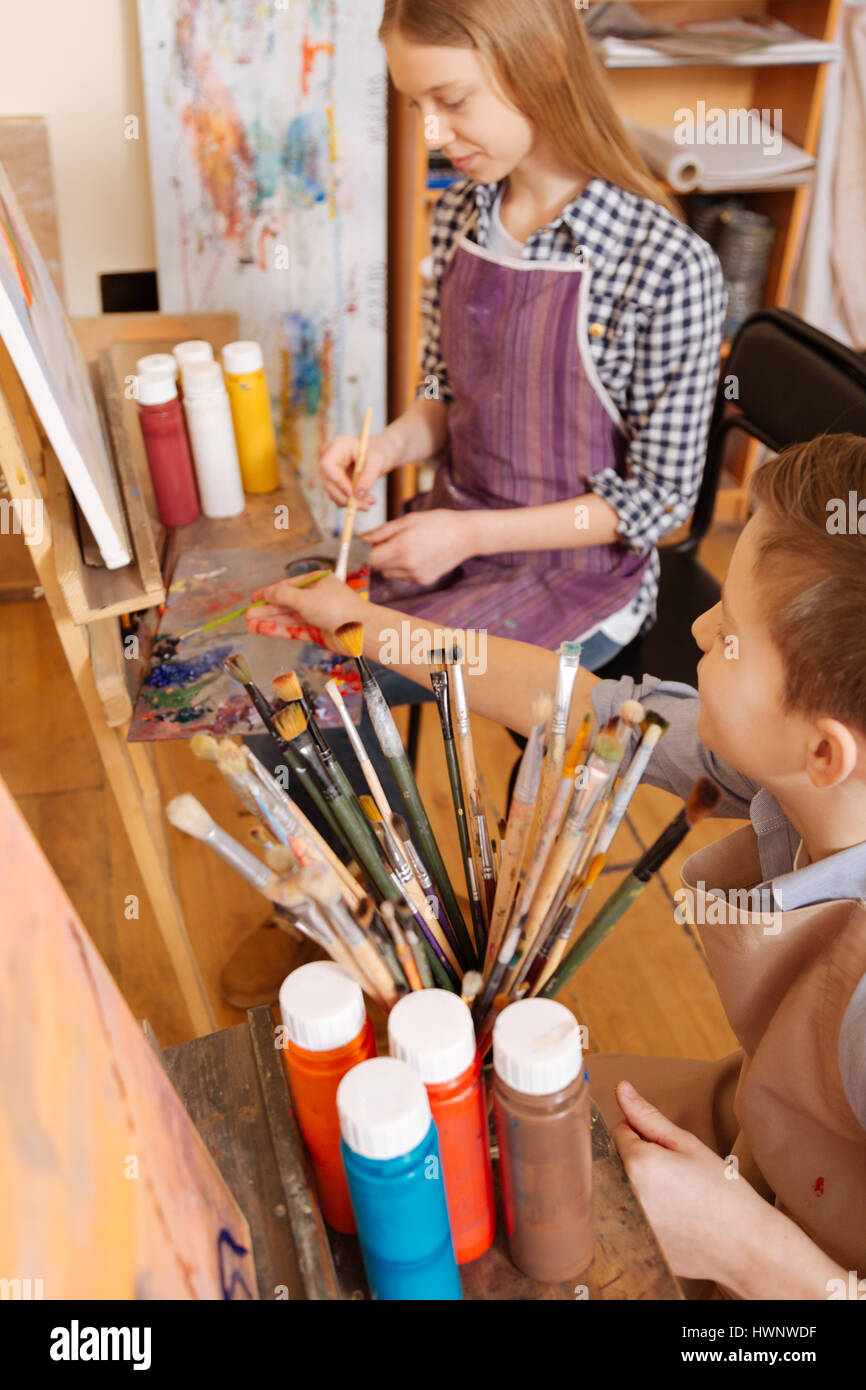 Having fun. Friendly joyful outgoing kids sitting in school and having ...