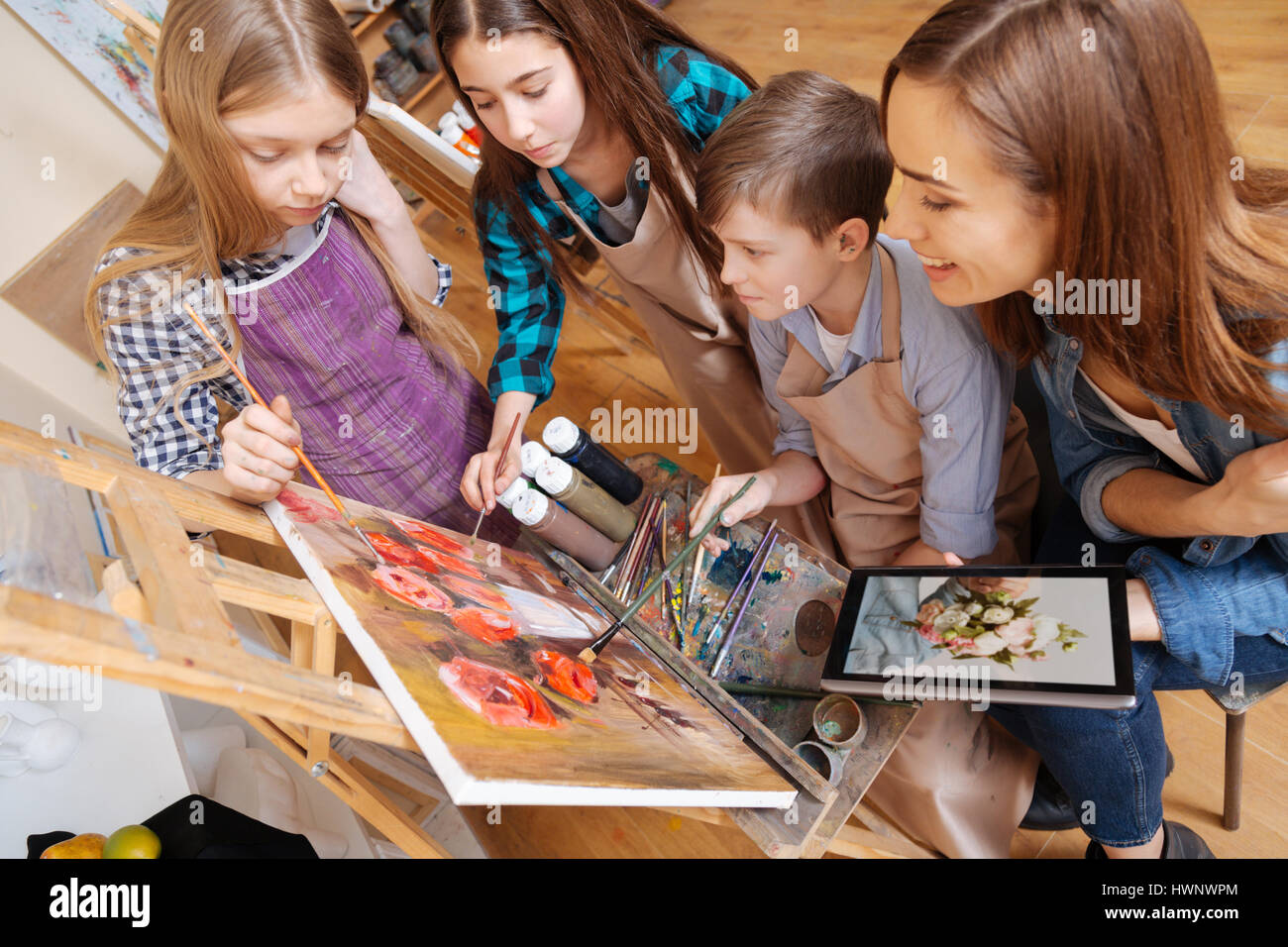 Enjoying art lesson . Positive helpful attentive teacher sitting in the ...