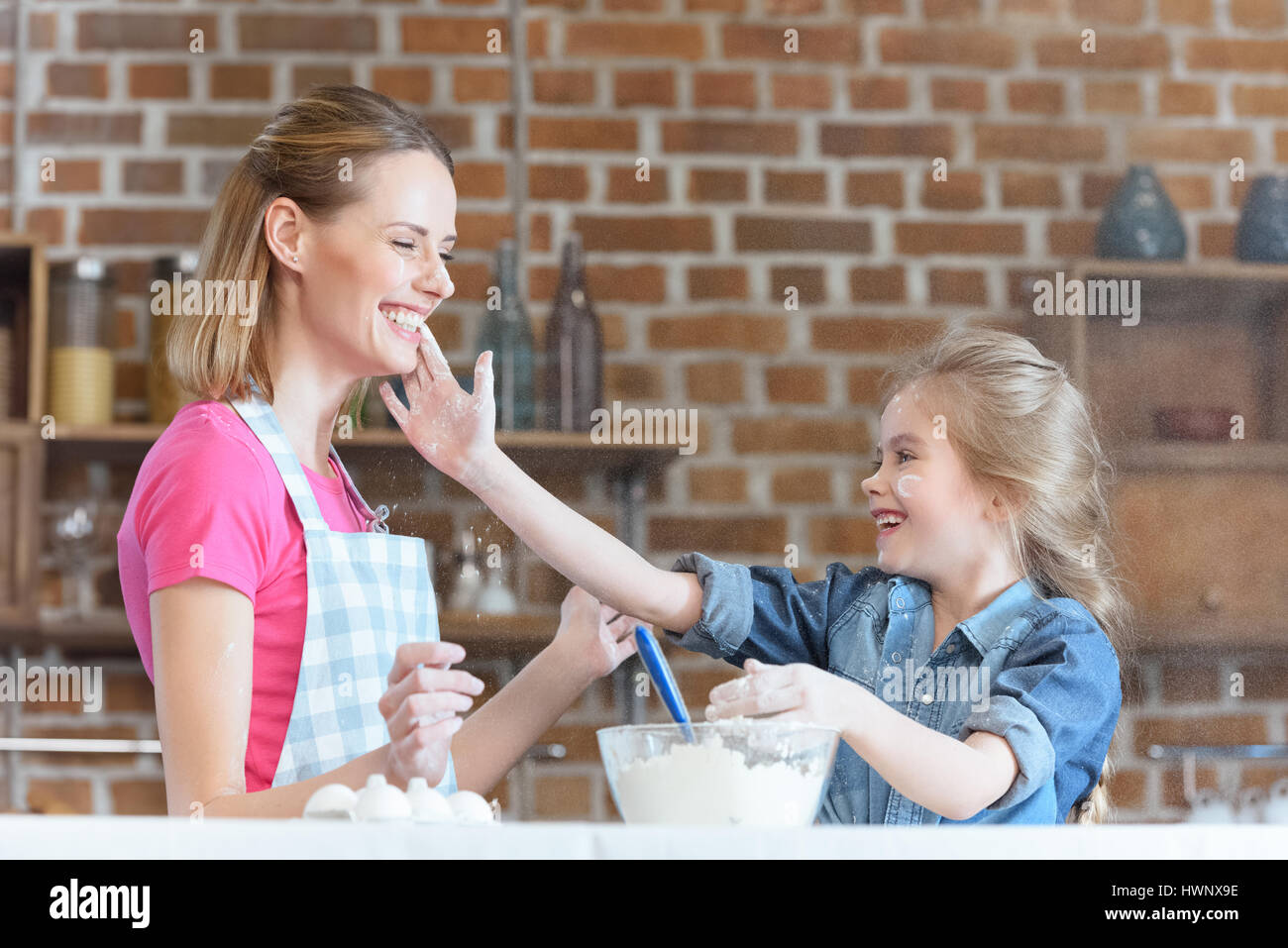 portrait of smiling mother and daughter having fun while cooking Stock ...