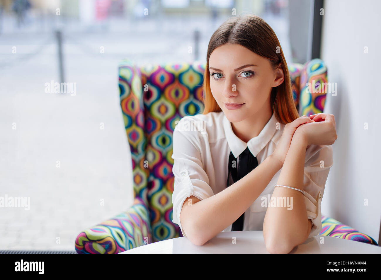 Pretty girl sitting on the bench in cafe place and looking forward ...