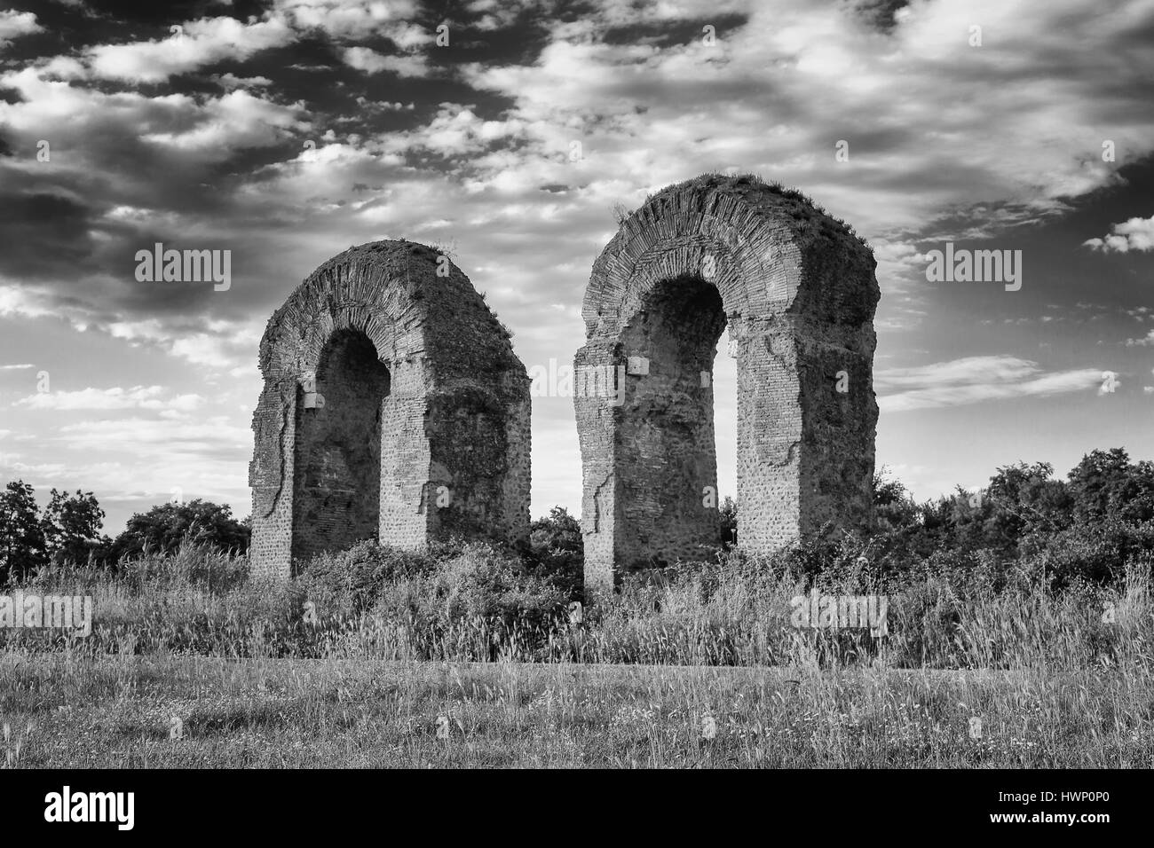 Arches of an ancient Roman aqueduct in red blocks of clay. A path runs ...