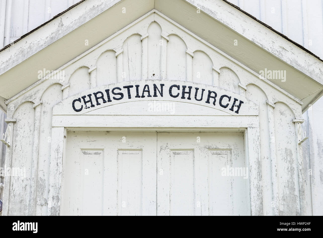 Close up of a Christian Church sign above the doors to a white painted ...