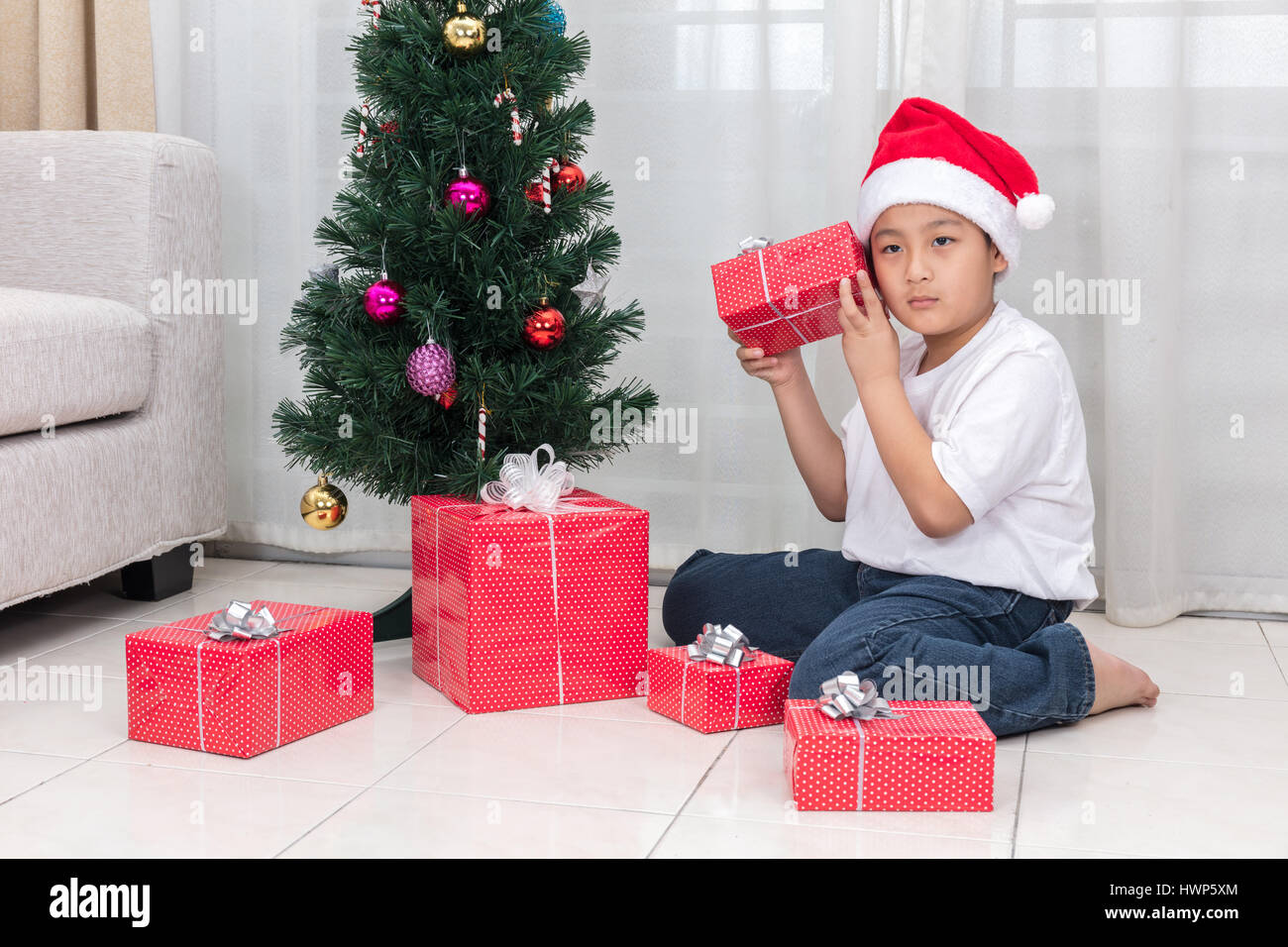 Asian Chinese little boy holding Christmas gift box in the living room ...