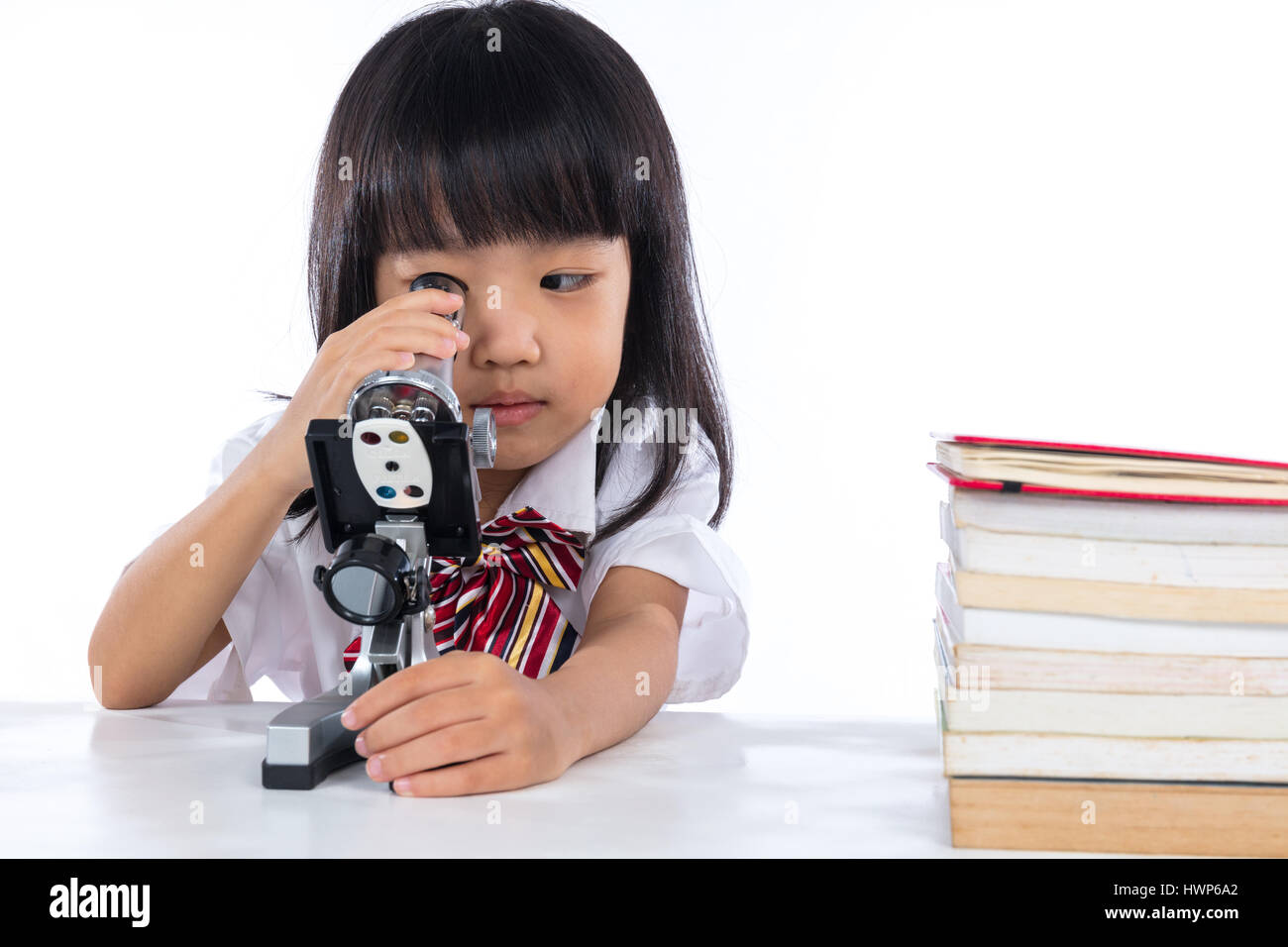Asian Chinese little girl looking through microscope in isolated white ...