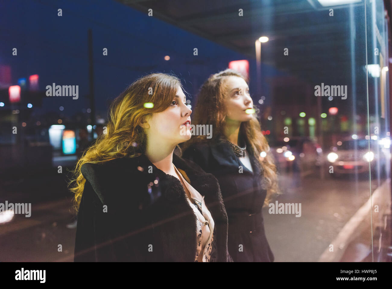 Two young beautiful caucasian women at the bus stop view through window ...