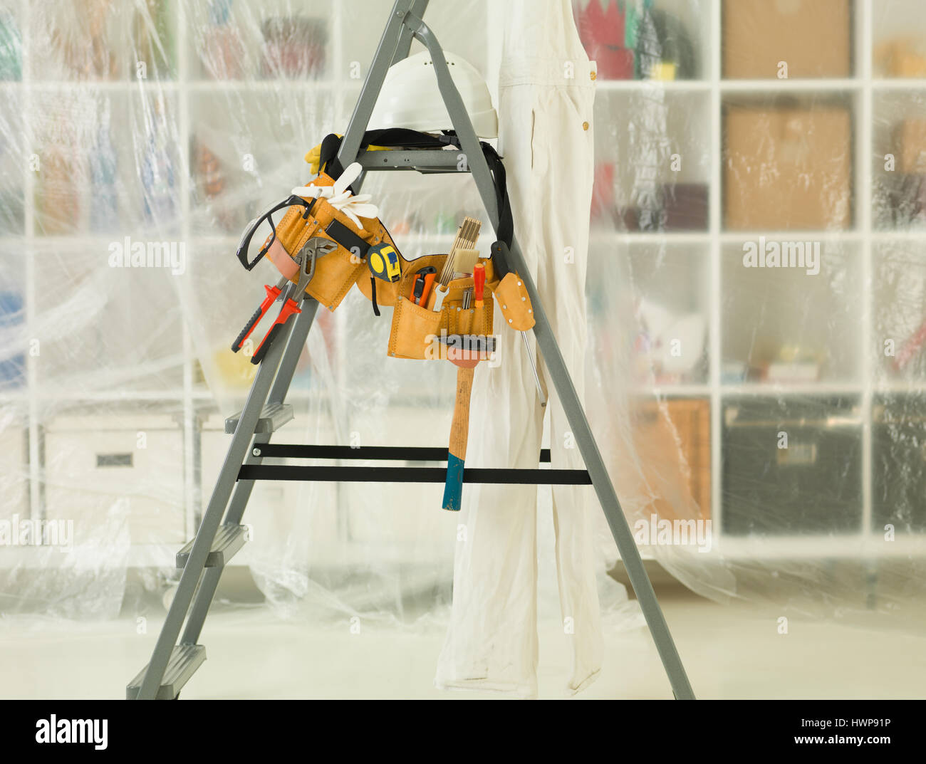 Tools belt and overalls hanging from an metal ladder. The renovation of ...