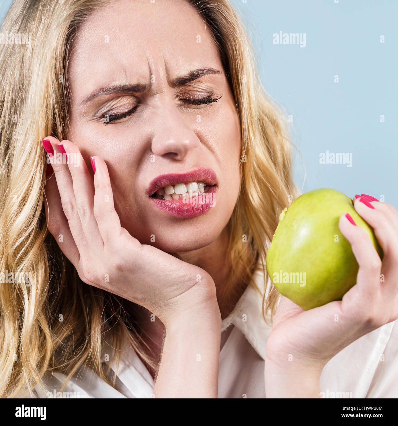 Woman feels toothpain because of sensitive gums and eating green apple ...