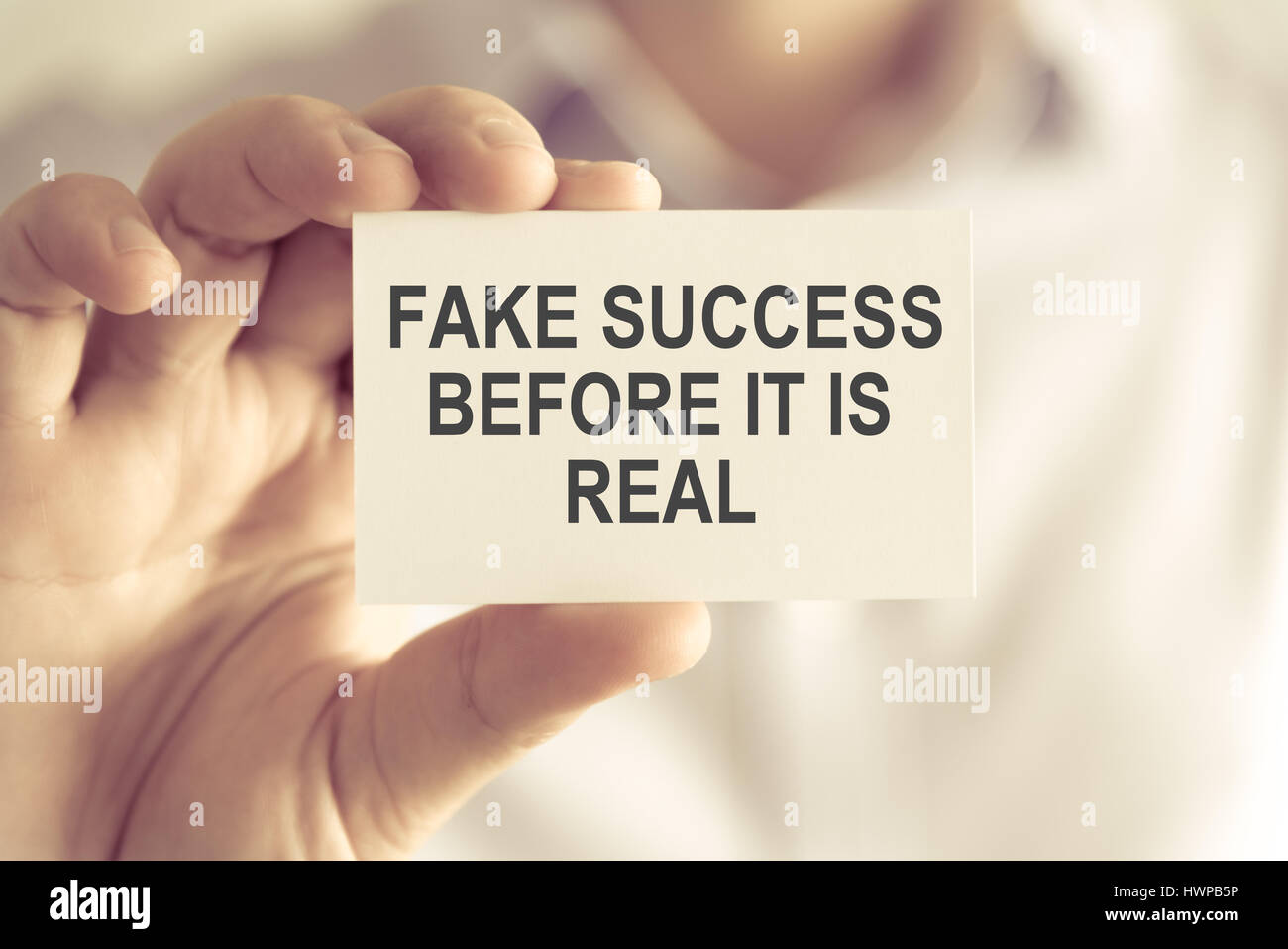 Closeup on businessman holding a card with text FAKE SUCCESS BEFORE IT ...