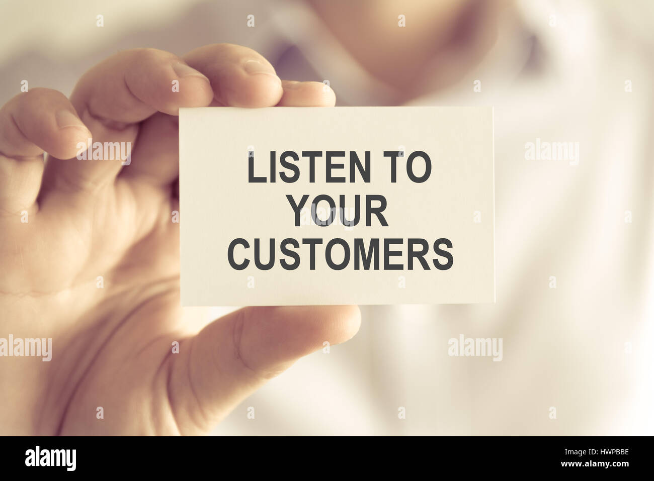 Closeup on businessman holding a card with text LISTEN TO YOUR ...