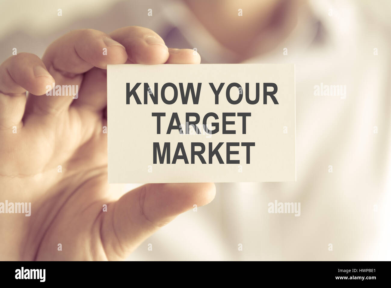 Closeup on businessman holding a card with text KNOW YOUR TARGET MARKET ...