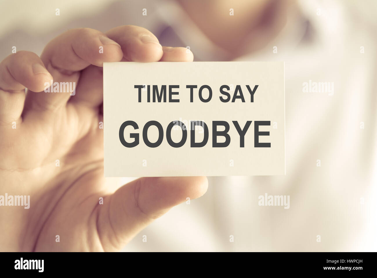 Closeup on businessman holding a card with text TIME TO SAY GOODBYE ...