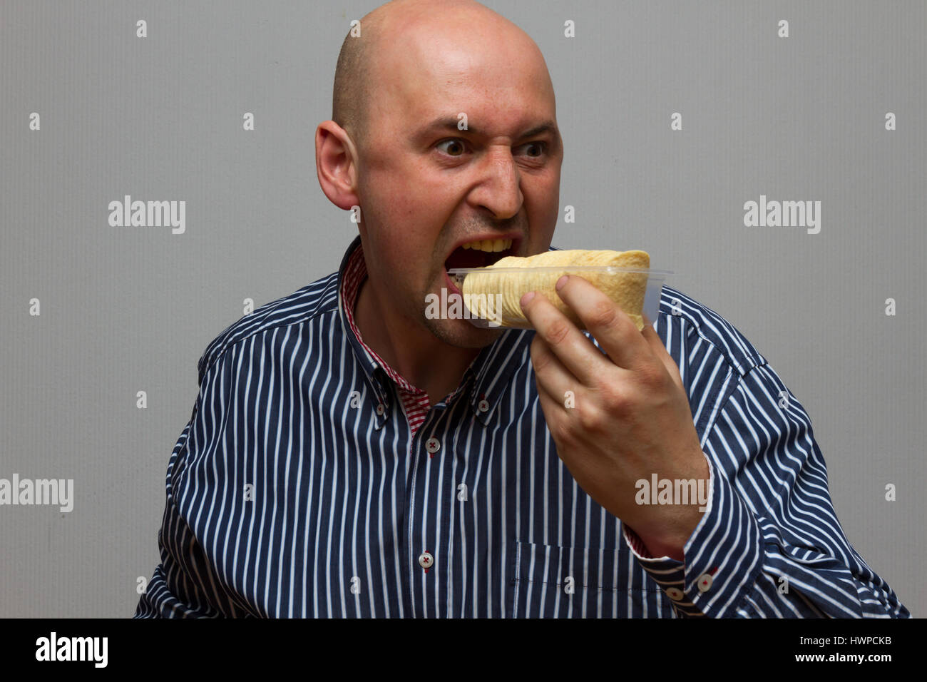 Man eating potato chips hurriedly Stock Photo - Alamy