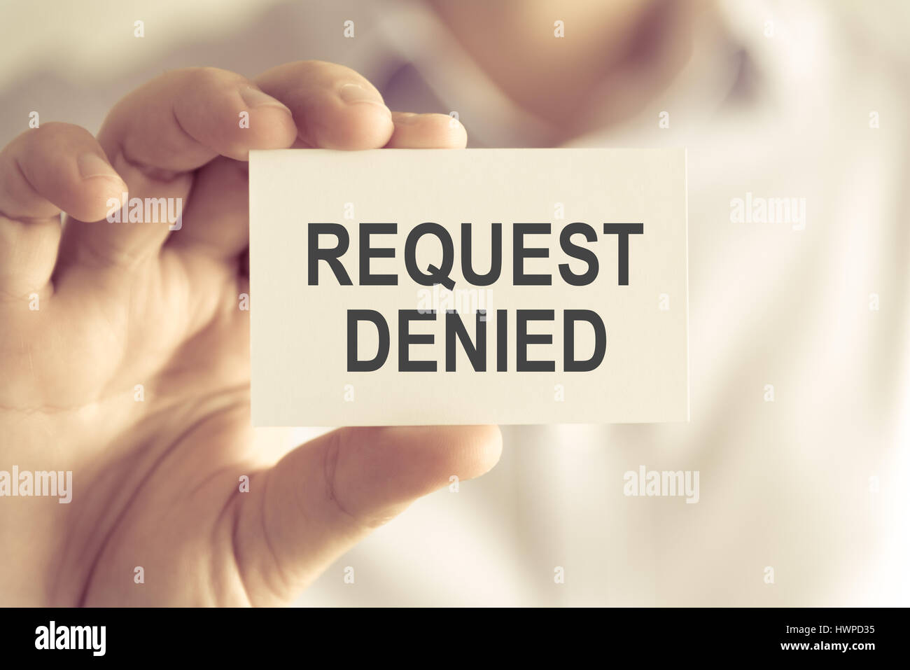 Closeup on businessman holding a card with text REQUEST DENIED ...