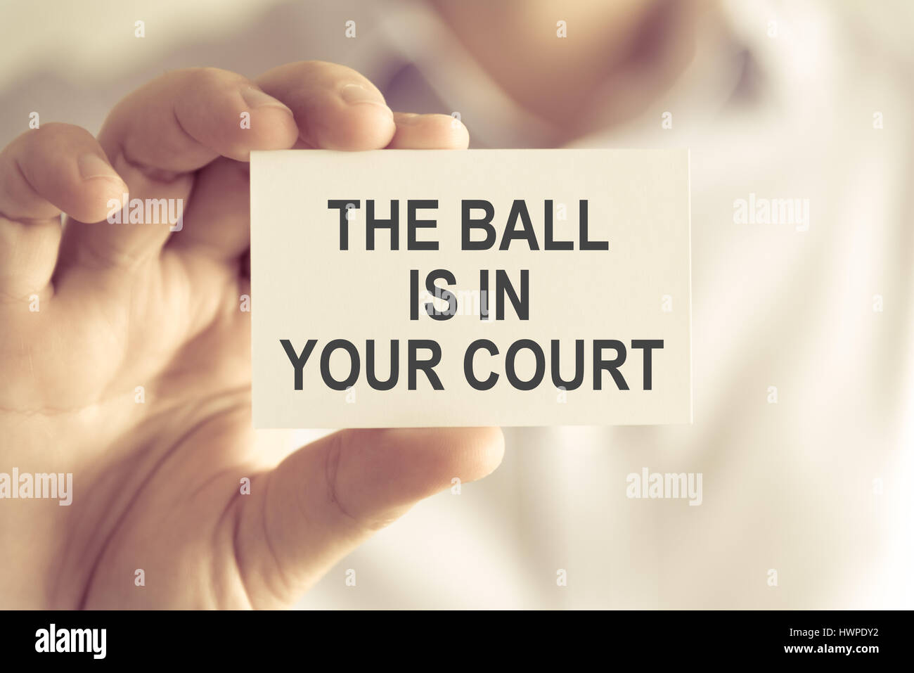 Closeup on businessman holding a card with text THE BALL IS IN YOUR ...