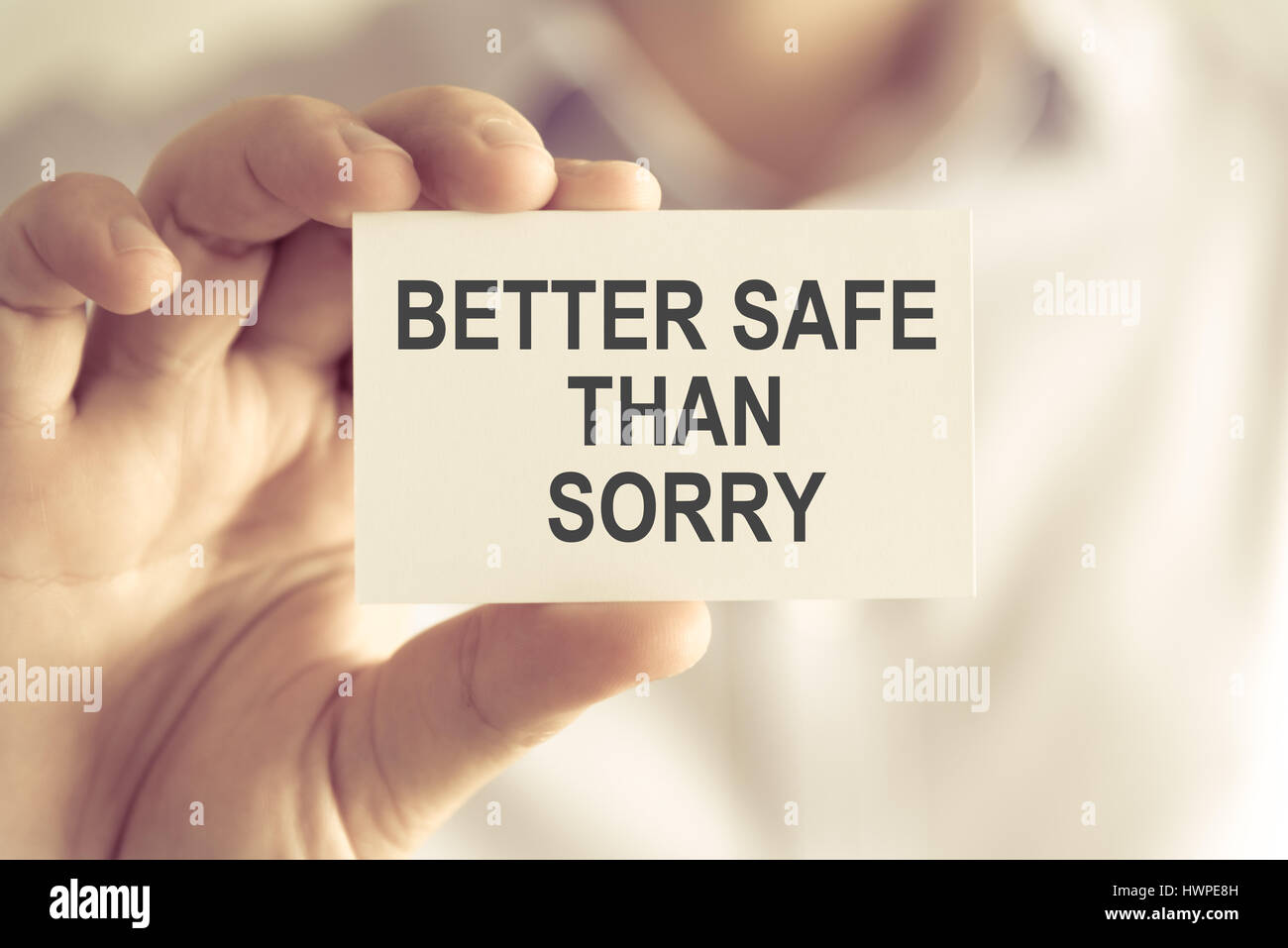 Closeup on businessman holding a card with text BETTER SAFE THAN SORRY ...
