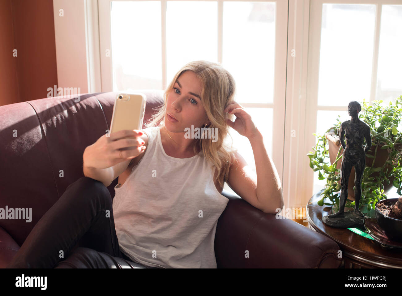 Woman taking selfie while sitting on armchair at home Stock Photo - Alamy