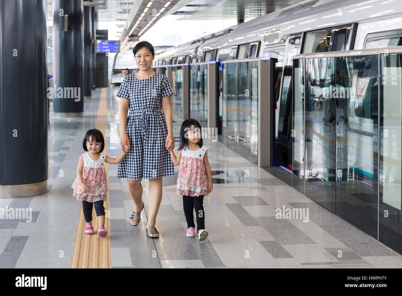 Asian Chinese mother and daughters waiting for transit at MRT station ...