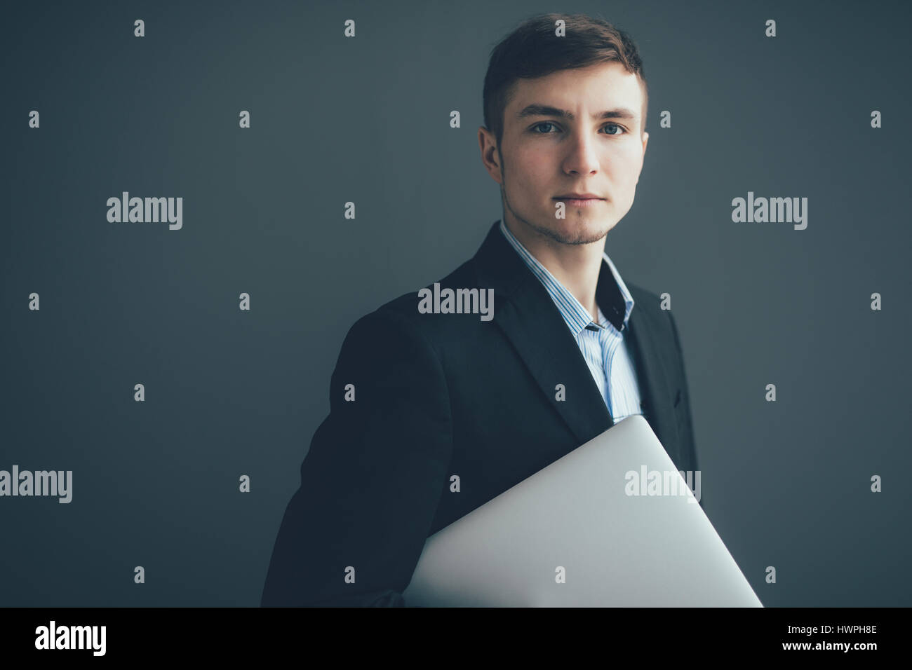Man standing on dark background with laptop Stock Photo - Alamy