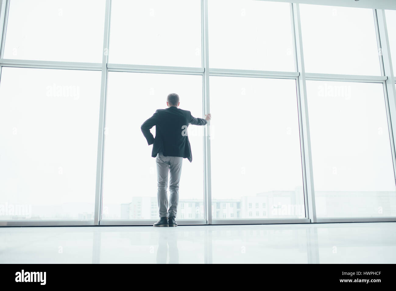 Stylish business man in the background of a large window in office ...