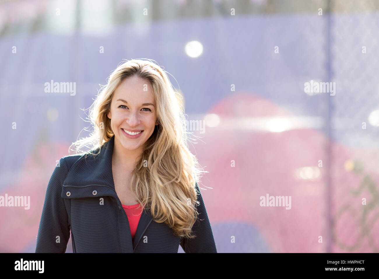 Portrait of smiling athlete standing by fence during sunny day Stock ...