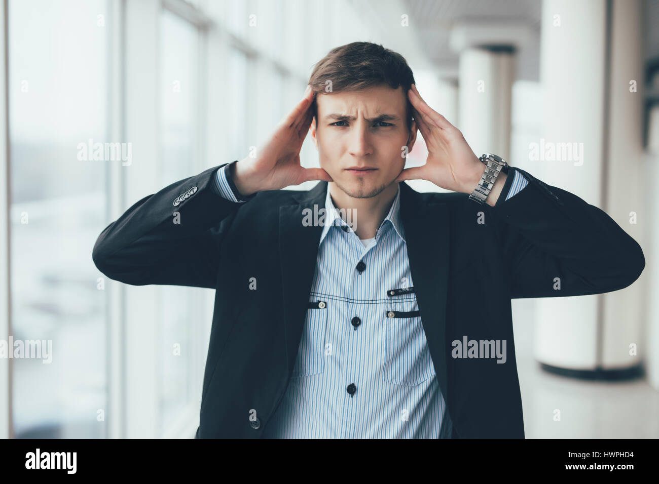 Young man with hands on head thinking in office room Stock Photo - Alamy