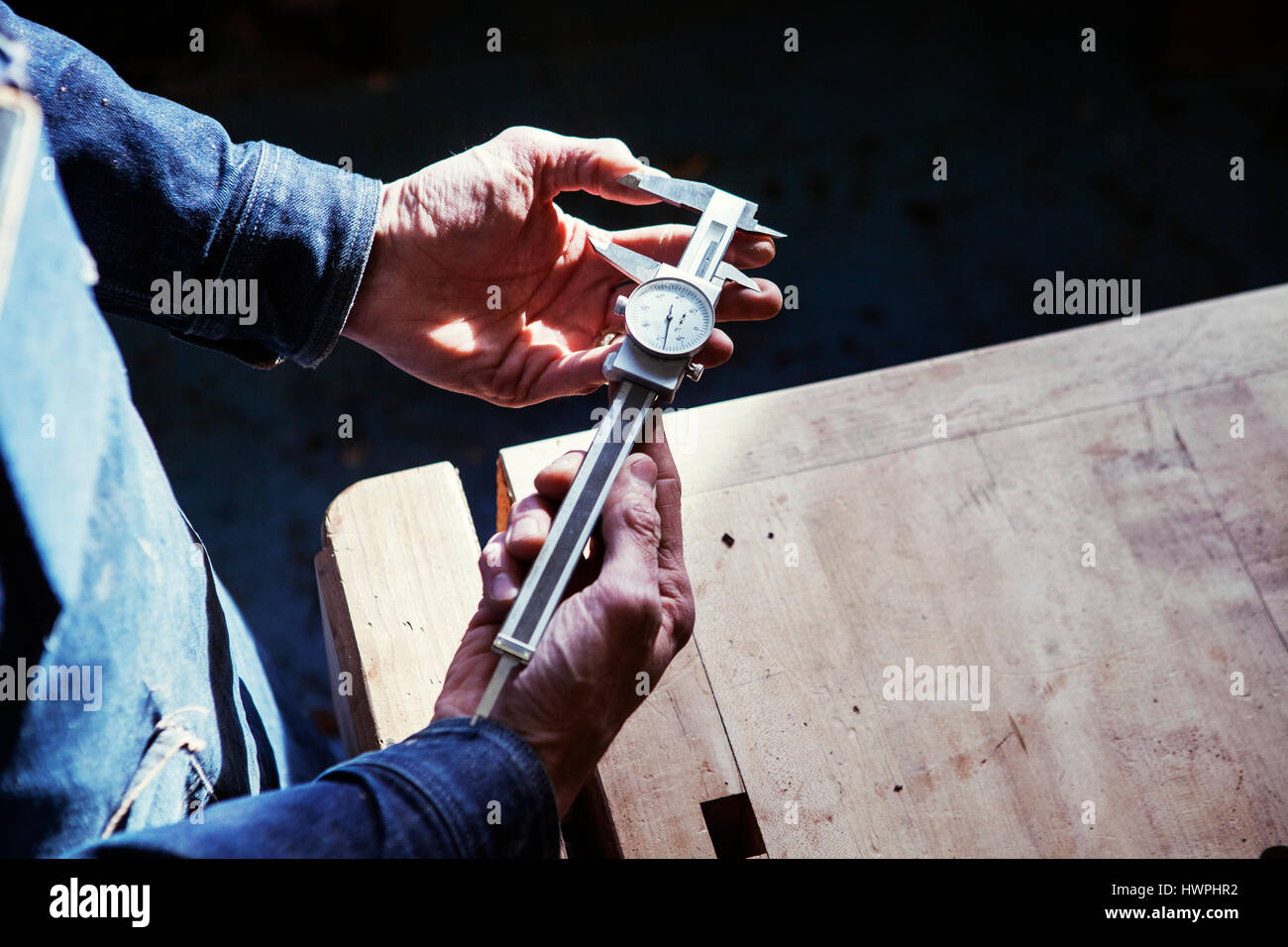 Midsection of carpenter holding vernier caliper at table in workshop ...