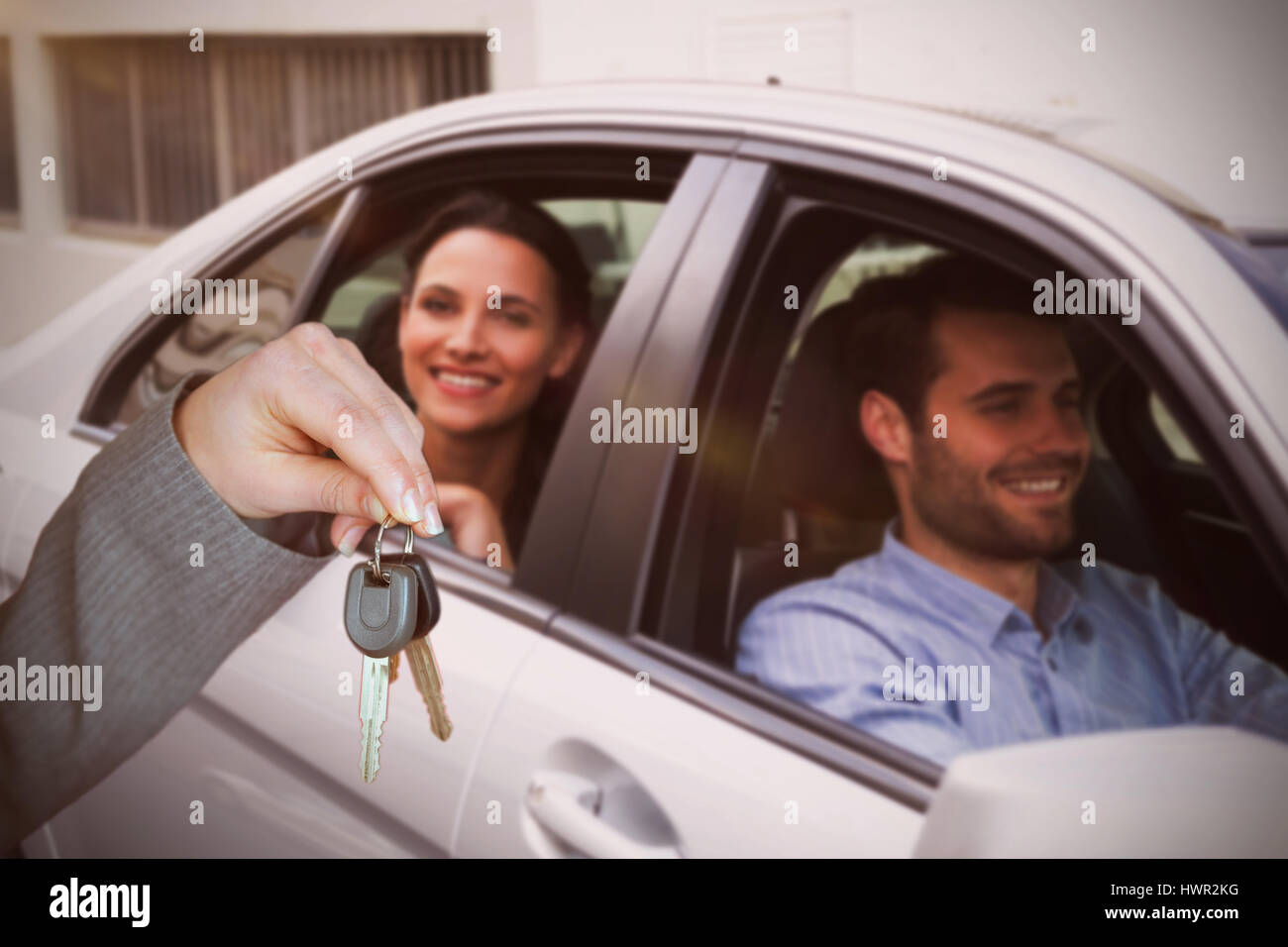Person handing keys to someone else against young couple smiling while ...