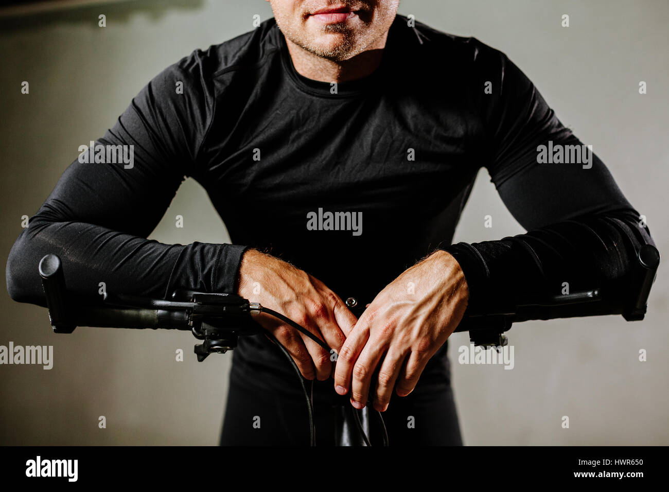 cycle man with bike indoors. Man in black cycling Apparel on gray wall ...