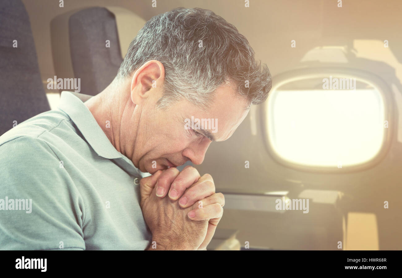 Tensed man standing against window against empty seat in modern plane ...
