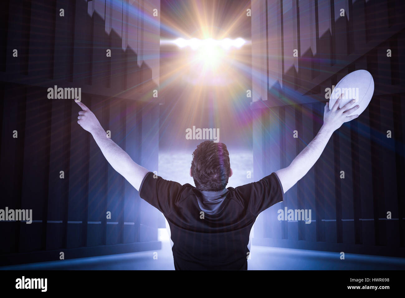 Back turned rugby player gesturing victory against football pitch under ...