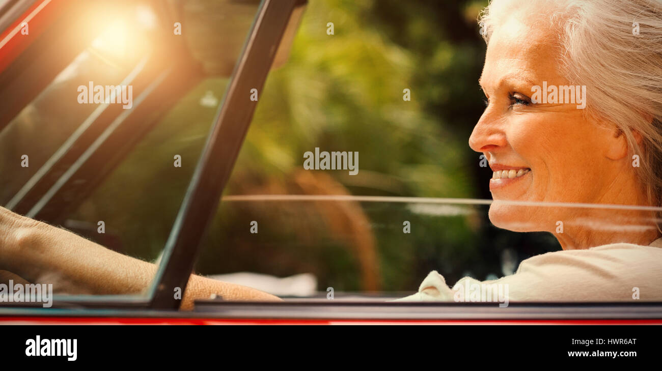 Smiling mature woman driving red convertible during sunny day Stock ...