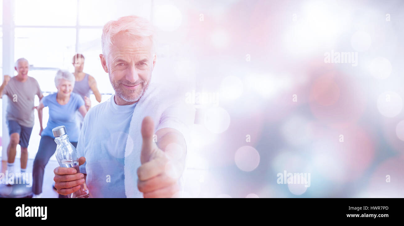 Man showing thumbs up sign with people exercising in background at ...