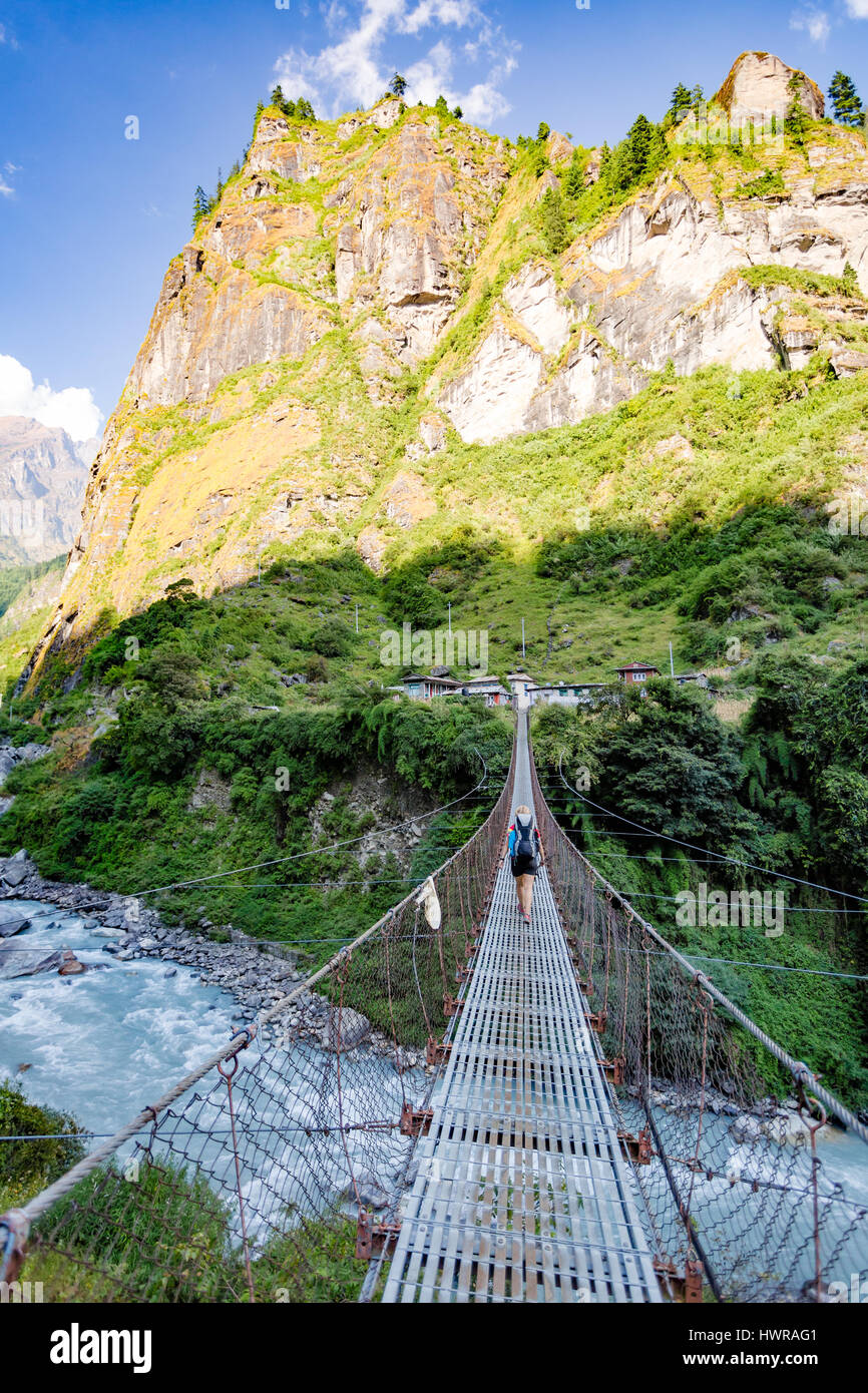 Woman backpacker crossing suspension bridge in Himalayas Nepal ...