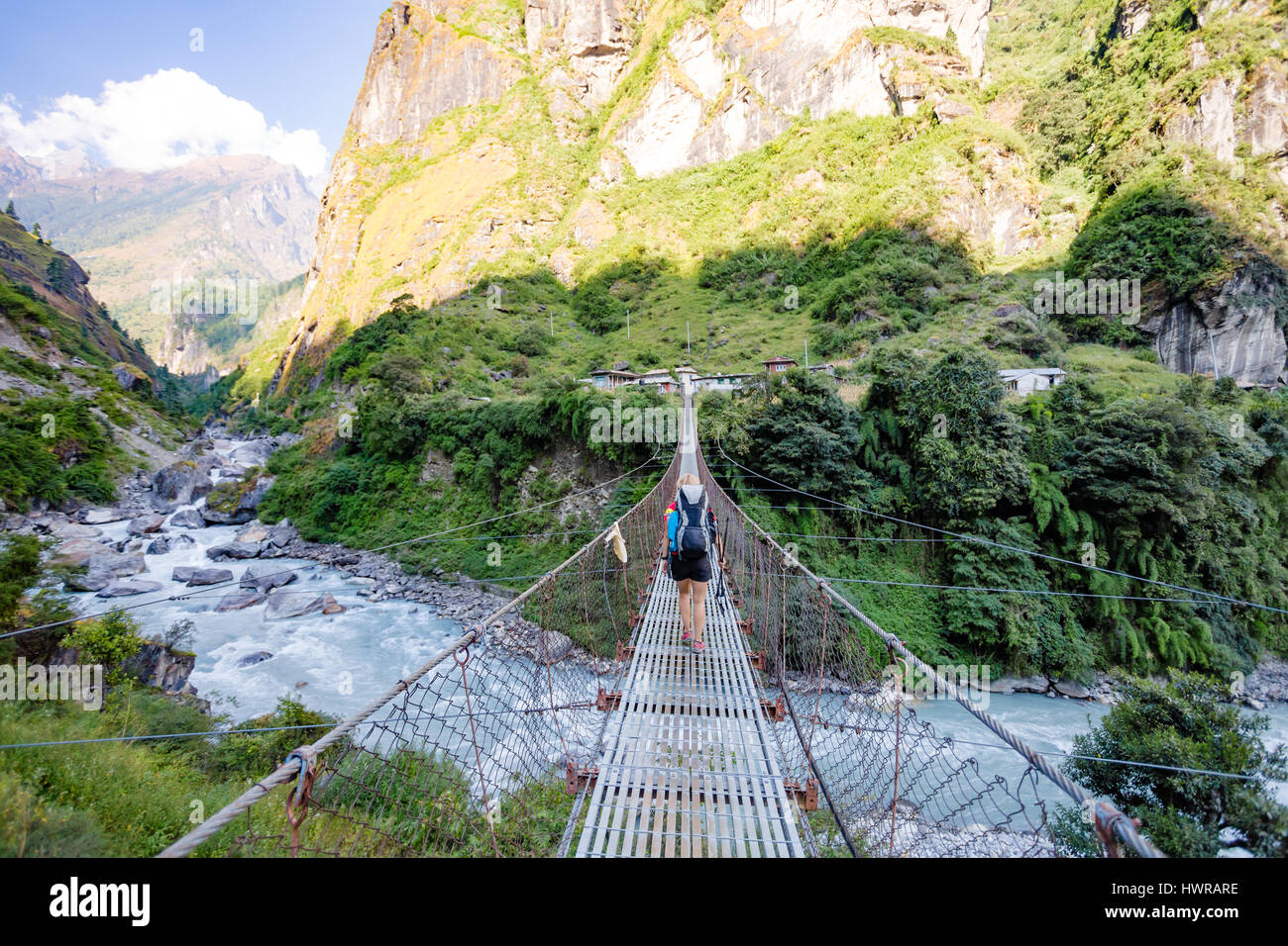 Woman backpacker crossing suspension bridge in Himalayas Nepal ...