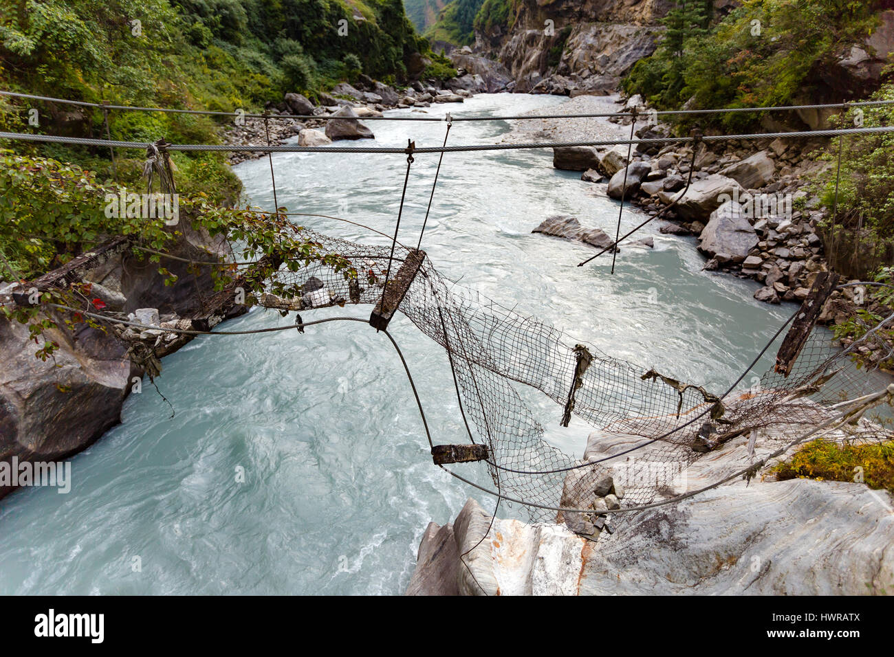 Broken Suspension Bridge in Himalayas Nepal. Looking at river in canyon ...