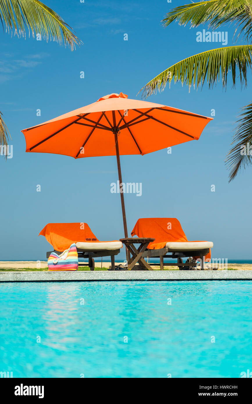 Deckchairs in tropical resort hotel swimming pool Stock Photo - Alamy