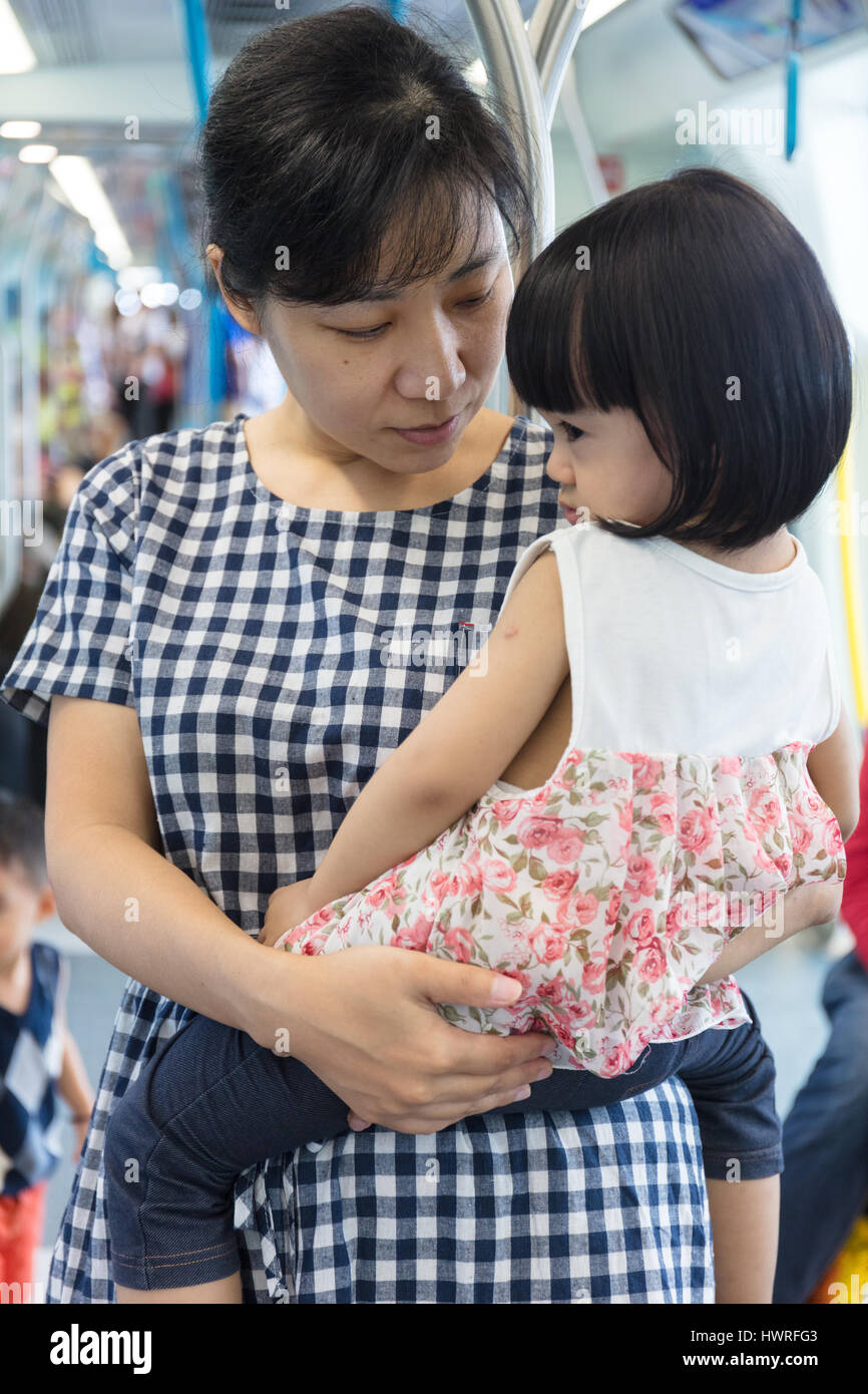 Asian Chinese mother carrying daughter inside a MRT transit in Kuala ...