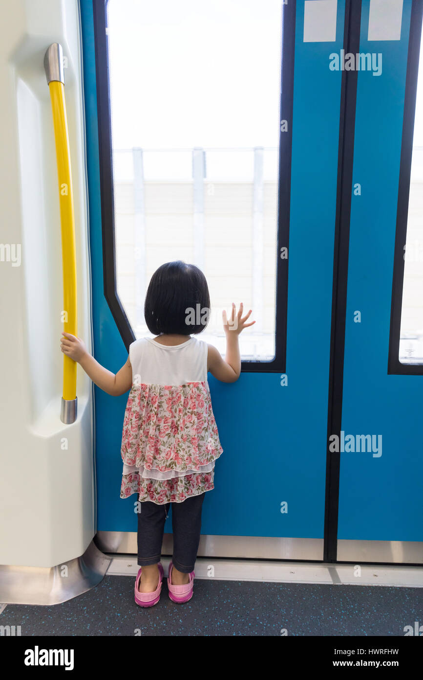 Asian Chinese little girl inside a MRT transit looking far way beside ...