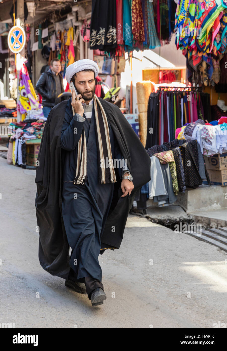 White-turbaned mullah striding through the bazaar at Khorramabad while ...