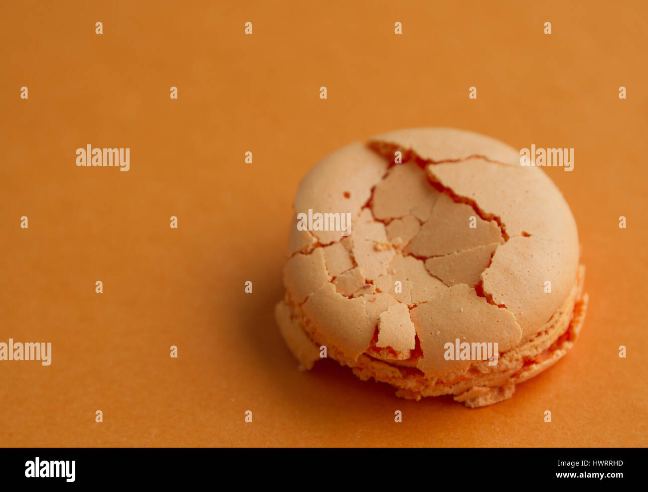 Orange single crushed macaroon over orange background with copy space ...