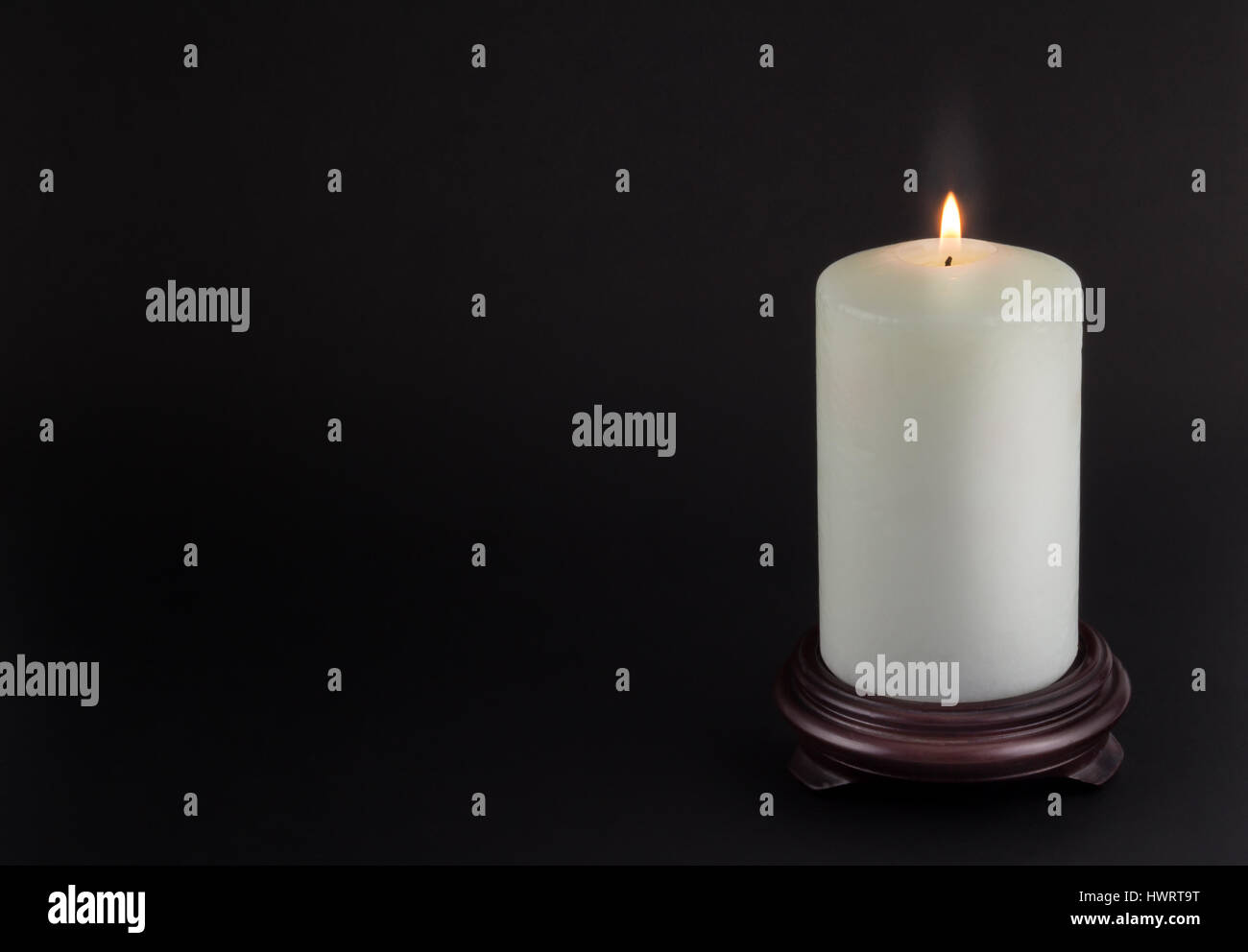 One white lit candle on wood stand isolated on black background Stock ...