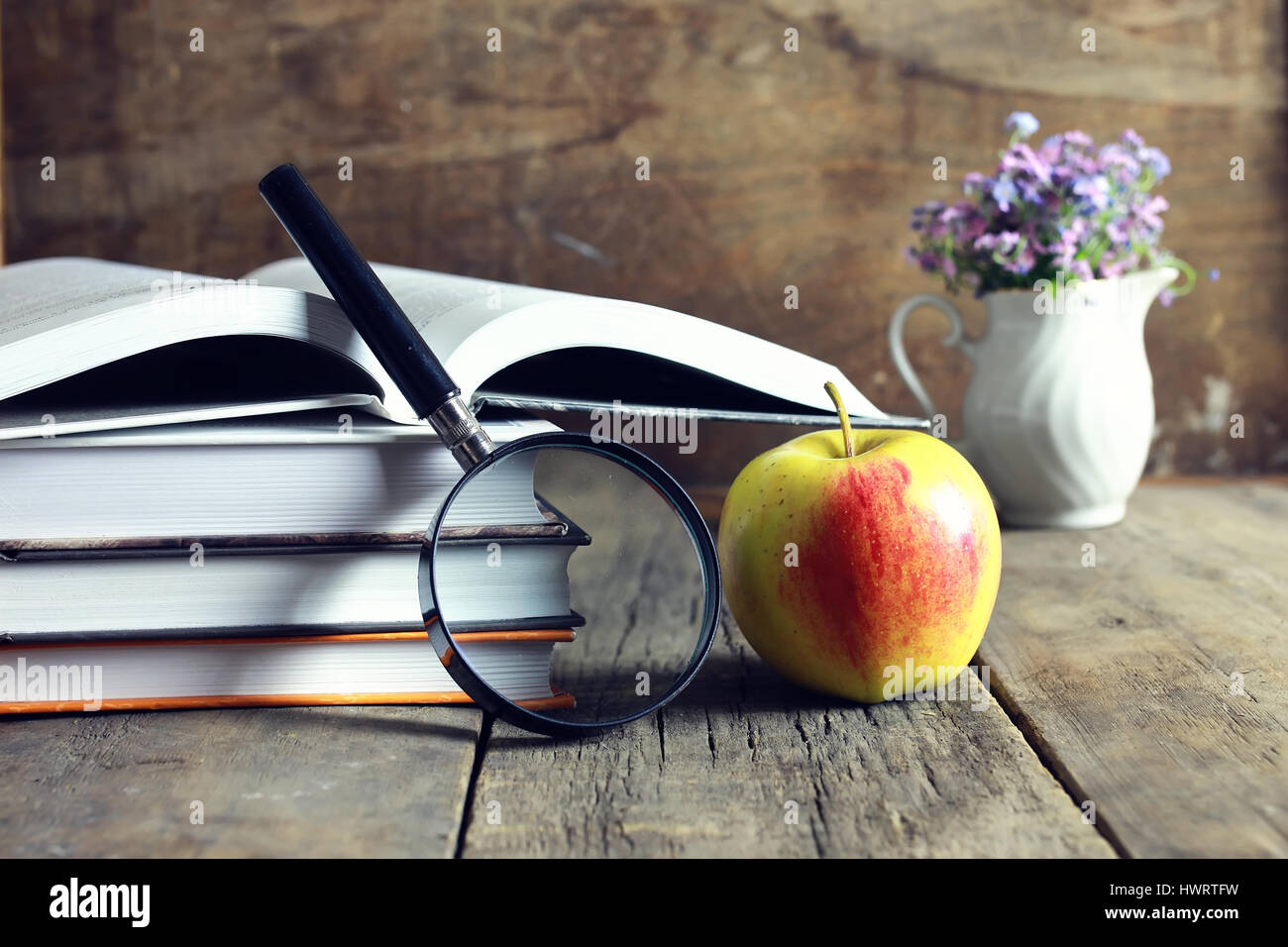 education book apple and magnifying glass Stock Photo - Alamy