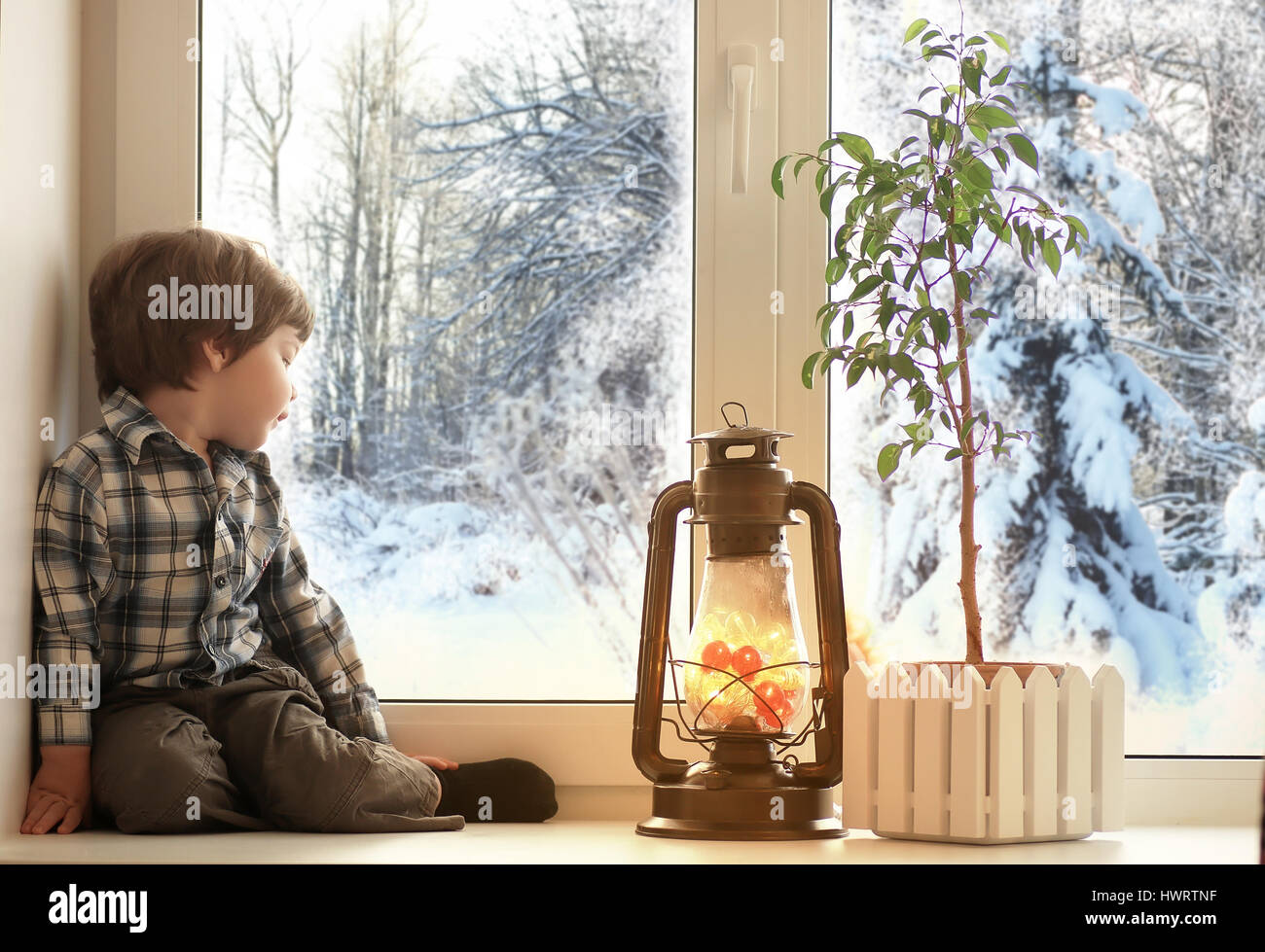 boy sitting on a white window sill and looks out the window Stock Photo ...