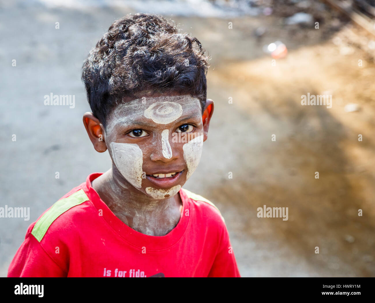 Local smiling young Burmese boy with typical patterned thanaka ...