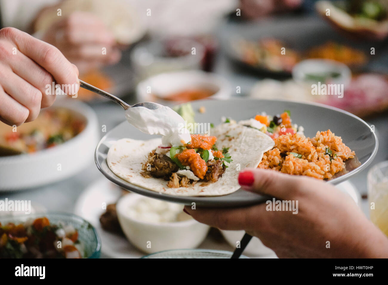 Cropped hands of friends making taco at dining table Stock Photo - Alamy