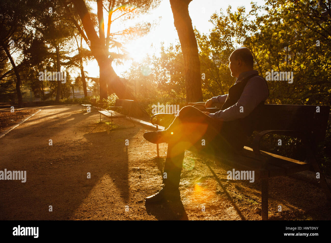 Side view of thoughtful man sitting on bench at park Stock Photo - Alamy