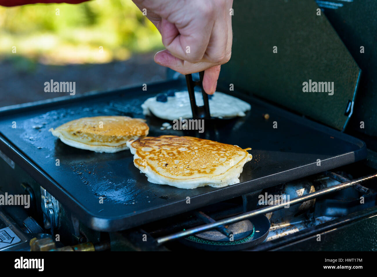 Cropped hand of man making pancakes at campsite Stock Photo - Alamy