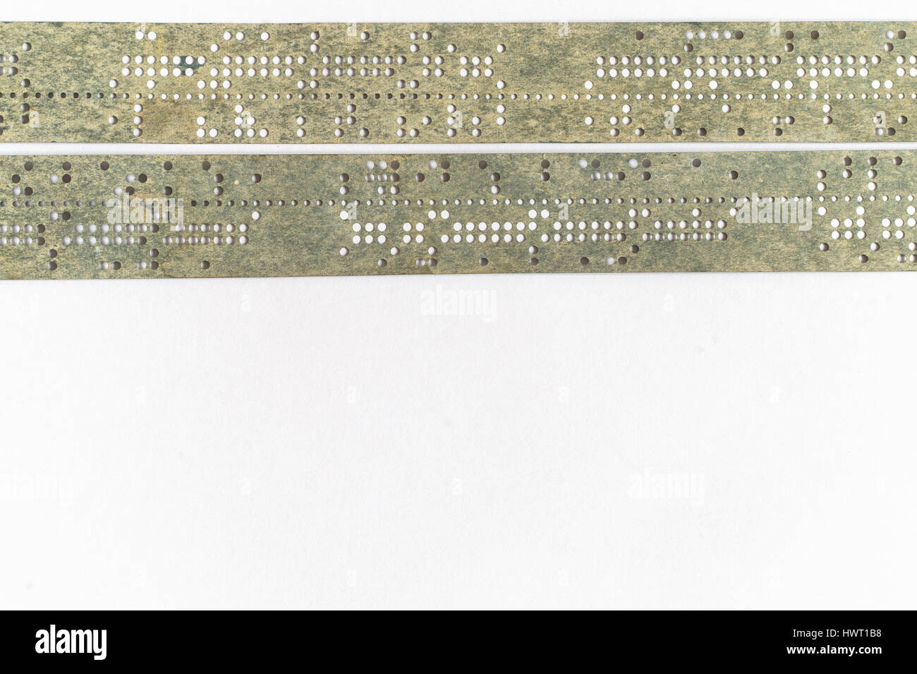 Strips of old punched tape on white surface Stock Photo - Alamy