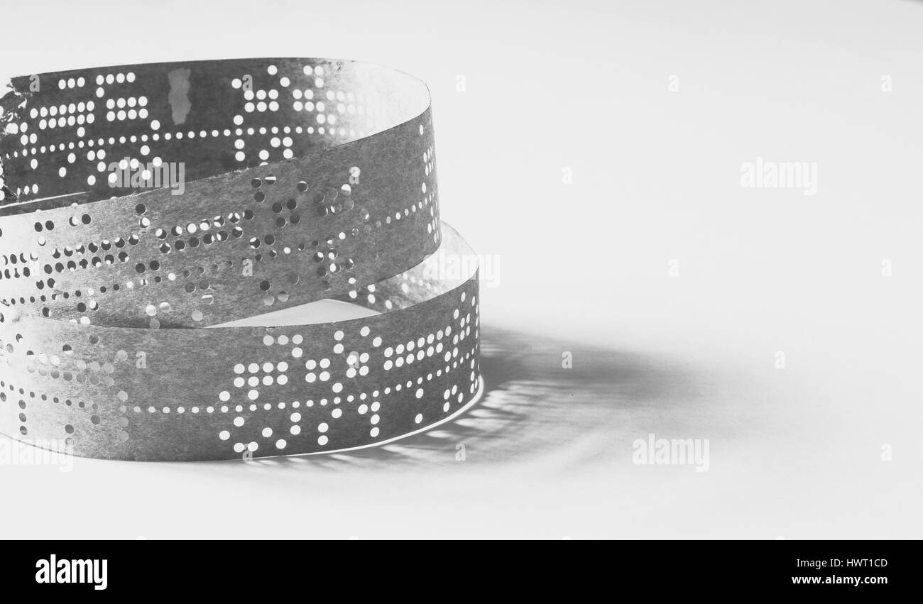 Strips of old punched tape on white surface Stock Photo - Alamy